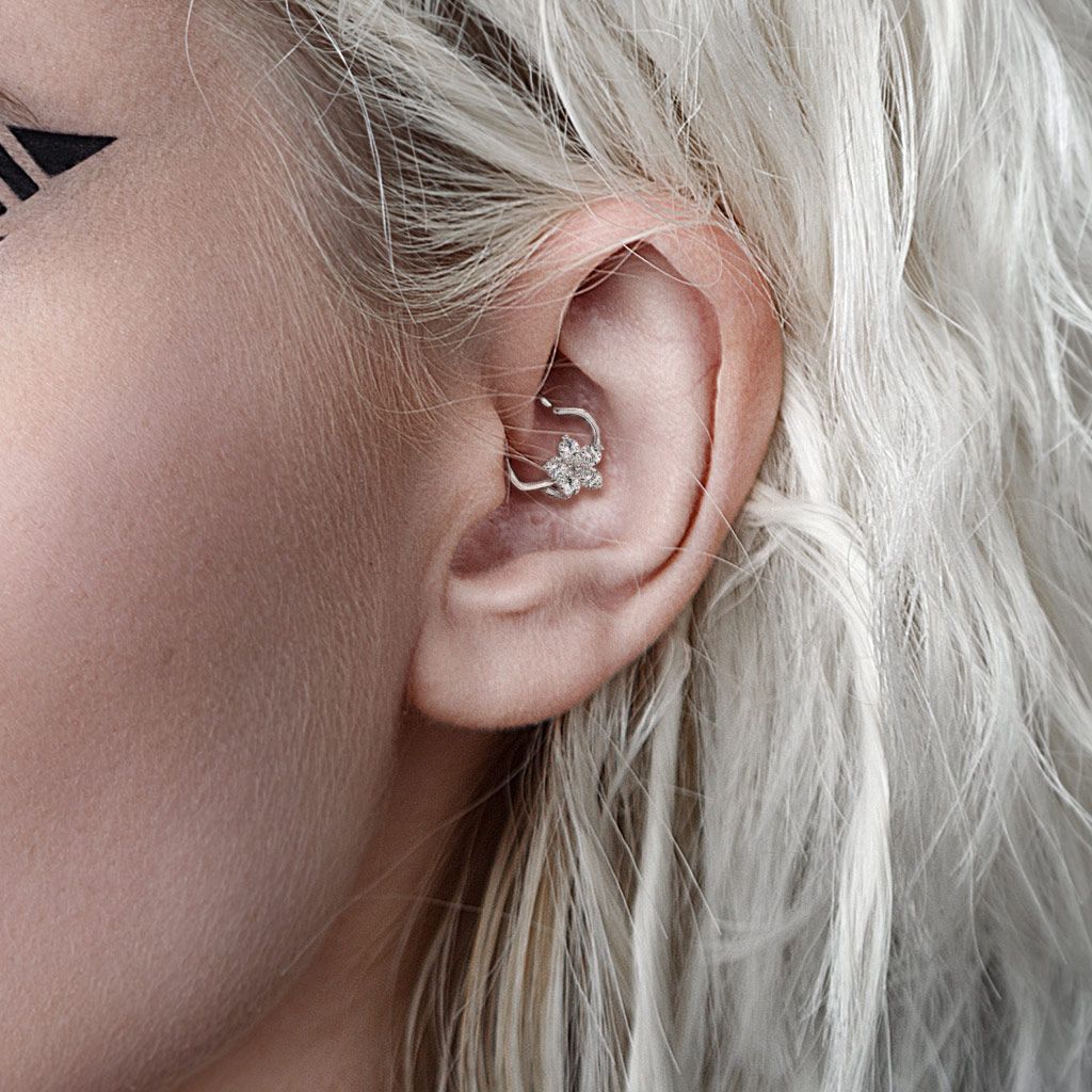 Vrouwelijke oorpiercing gevormd als een hartje met bloemetje